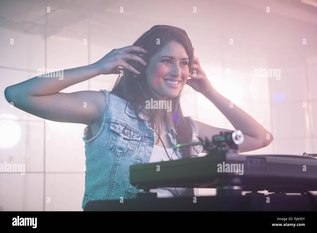 Pretty female DJ listening to the headphone while playing music Stock ...