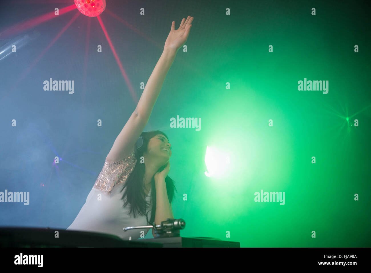 Pretty female DJ waving her hand while playing music Stock Photo - Alamy