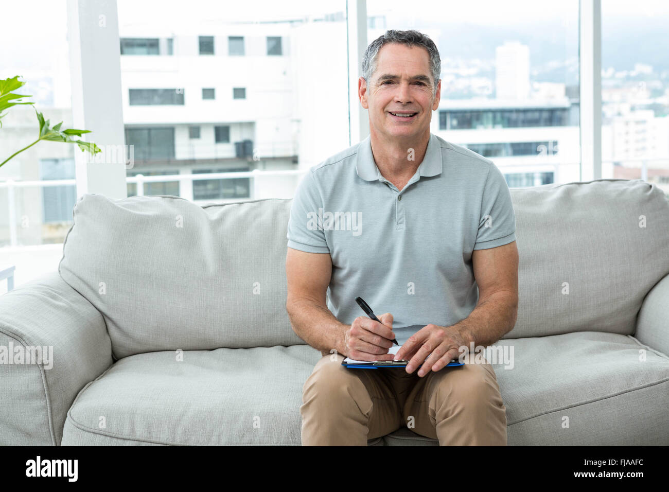 Man sitting on sofa and writing on notepad Stock Photo - Alamy