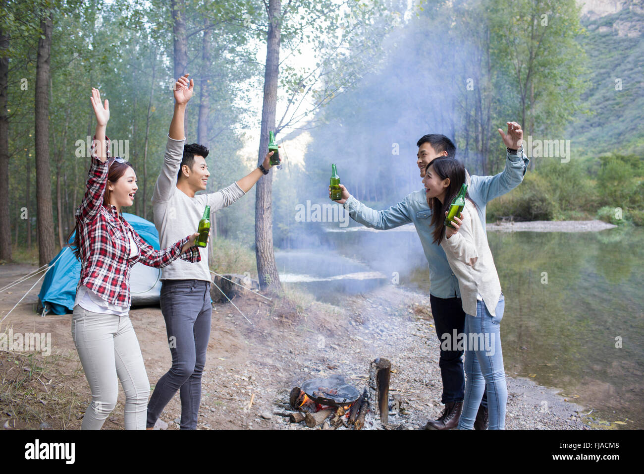 Young Chinese friends standing around campfire drinking beer Stock ...