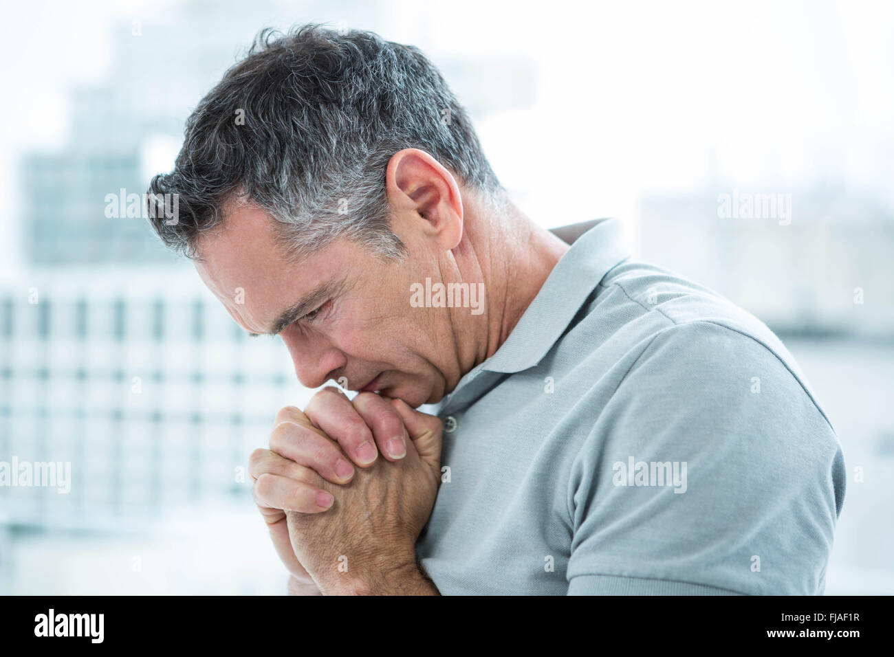 Tensed man standing against window Stock Photo - Alamy