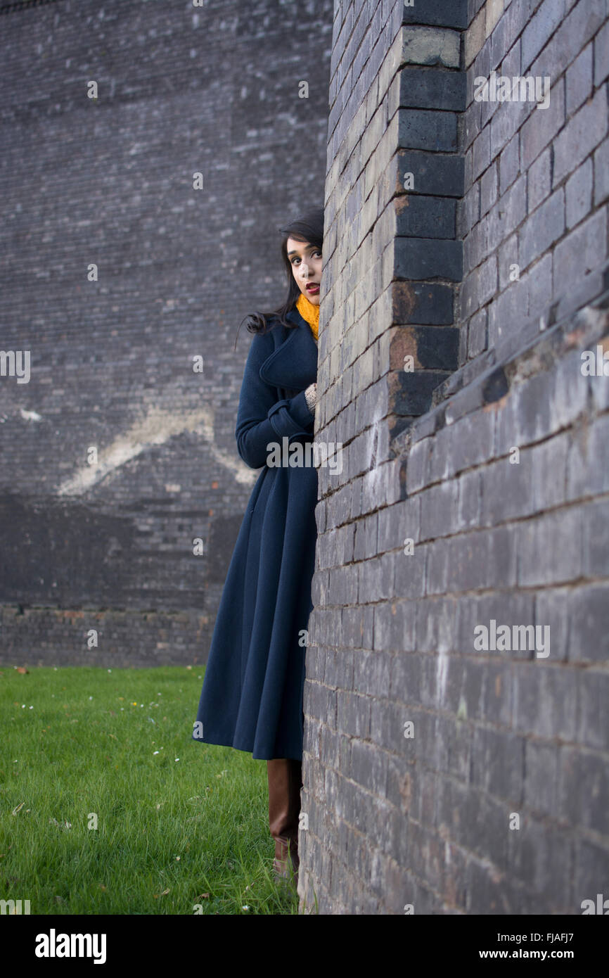 Young woman standing behind a wall outdoors Stock Photo - Alamy