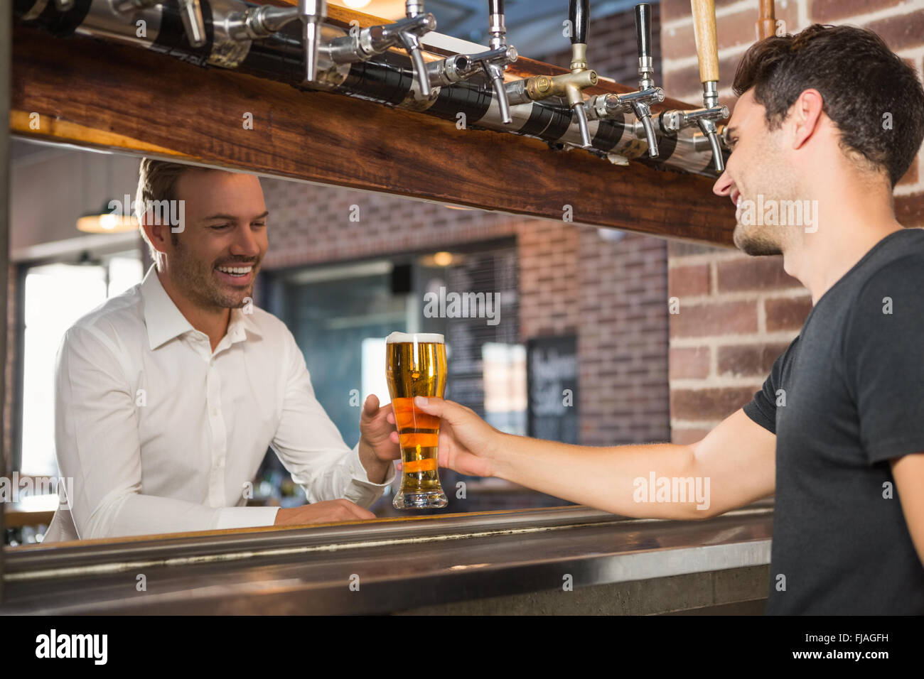 Handsome bar tender giving a pint for a customer Stock Photo - Alamy