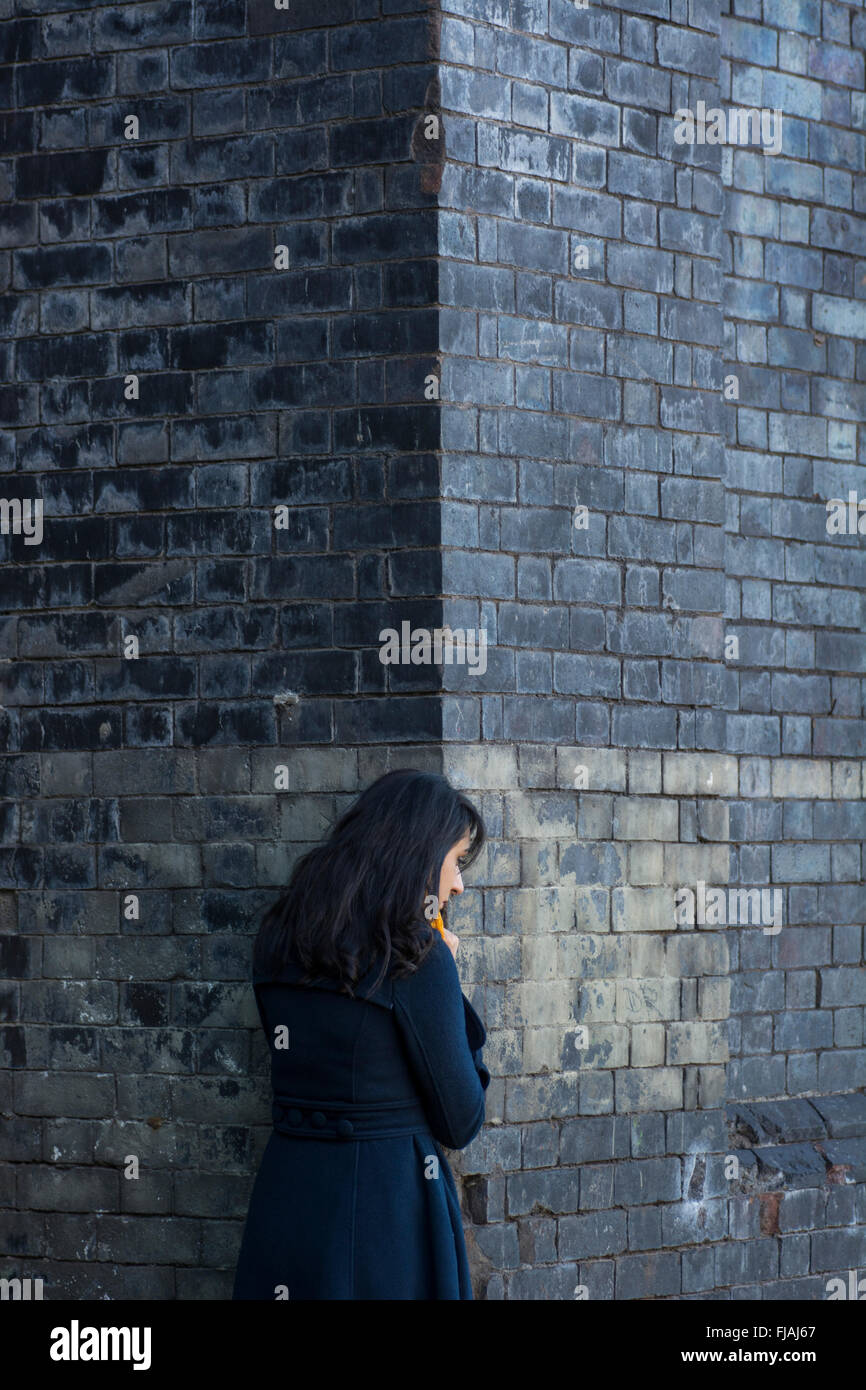 Young woman standing behind a wall outdoors Stock Photo - Alamy
