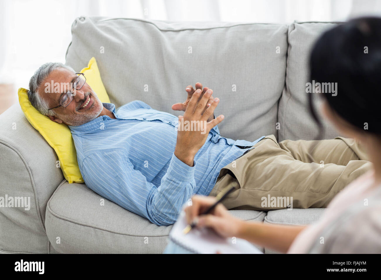 Female doctor writing on notepad while consulting a man Stock Photo - Alamy