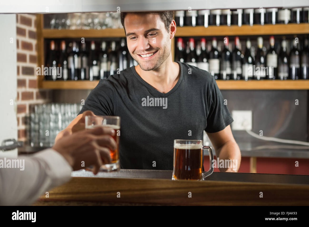 Handsome bar tender giving a pint to customer Stock Photo - Alamy