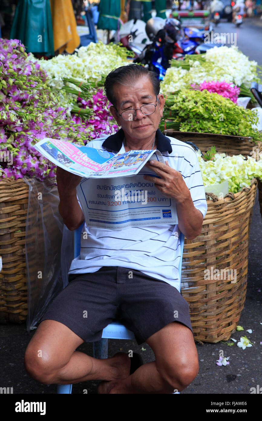 Man reading the paper in a Bangkok flower market Stock Photo - Alamy