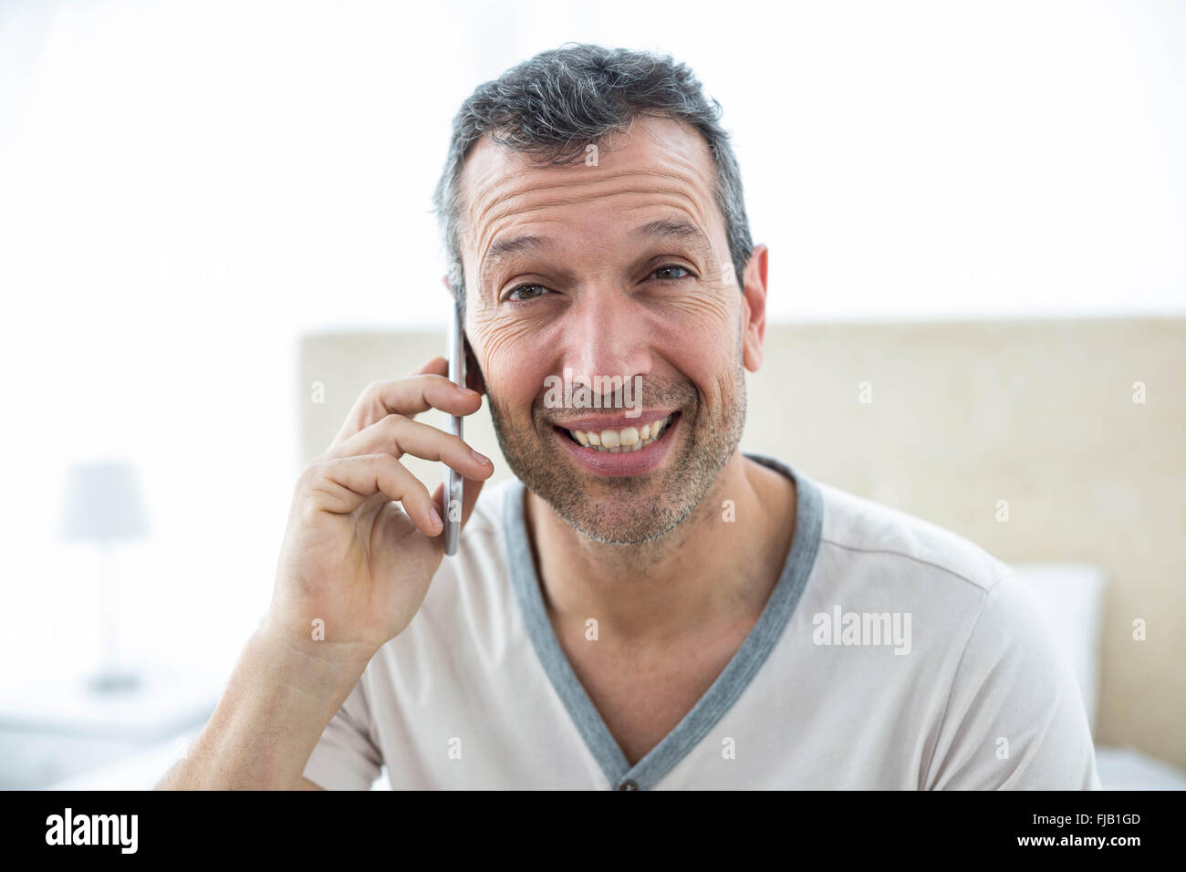 Man talking on smartphone in bedroom Stock Photo - Alamy
