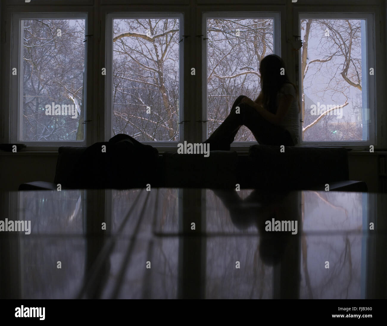 Woman looking out the window in winter Stock Photo - Alamy