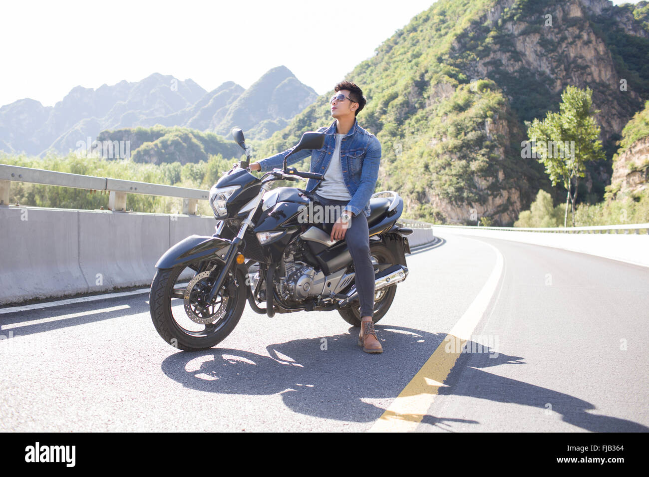 Young Chinese man riding motorcycle Stock Photo - Alamy