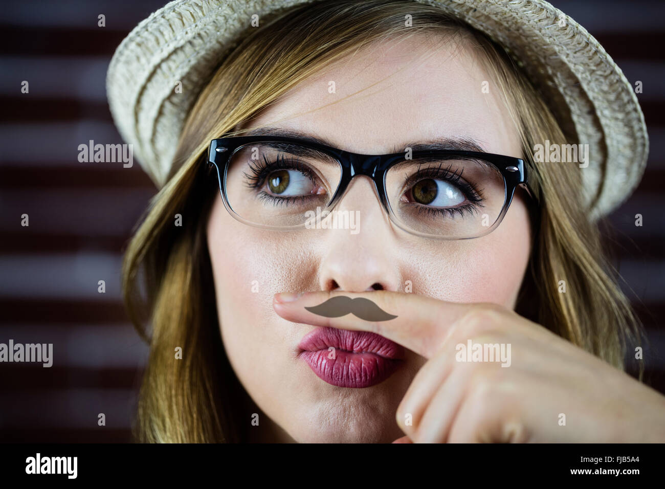 Pretty blonde woman doing a moustache with her finger Stock Photo - Alamy