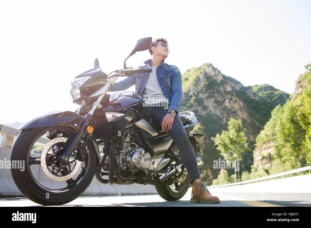 Young Chinese man riding motorcycle Stock Photo - Alamy