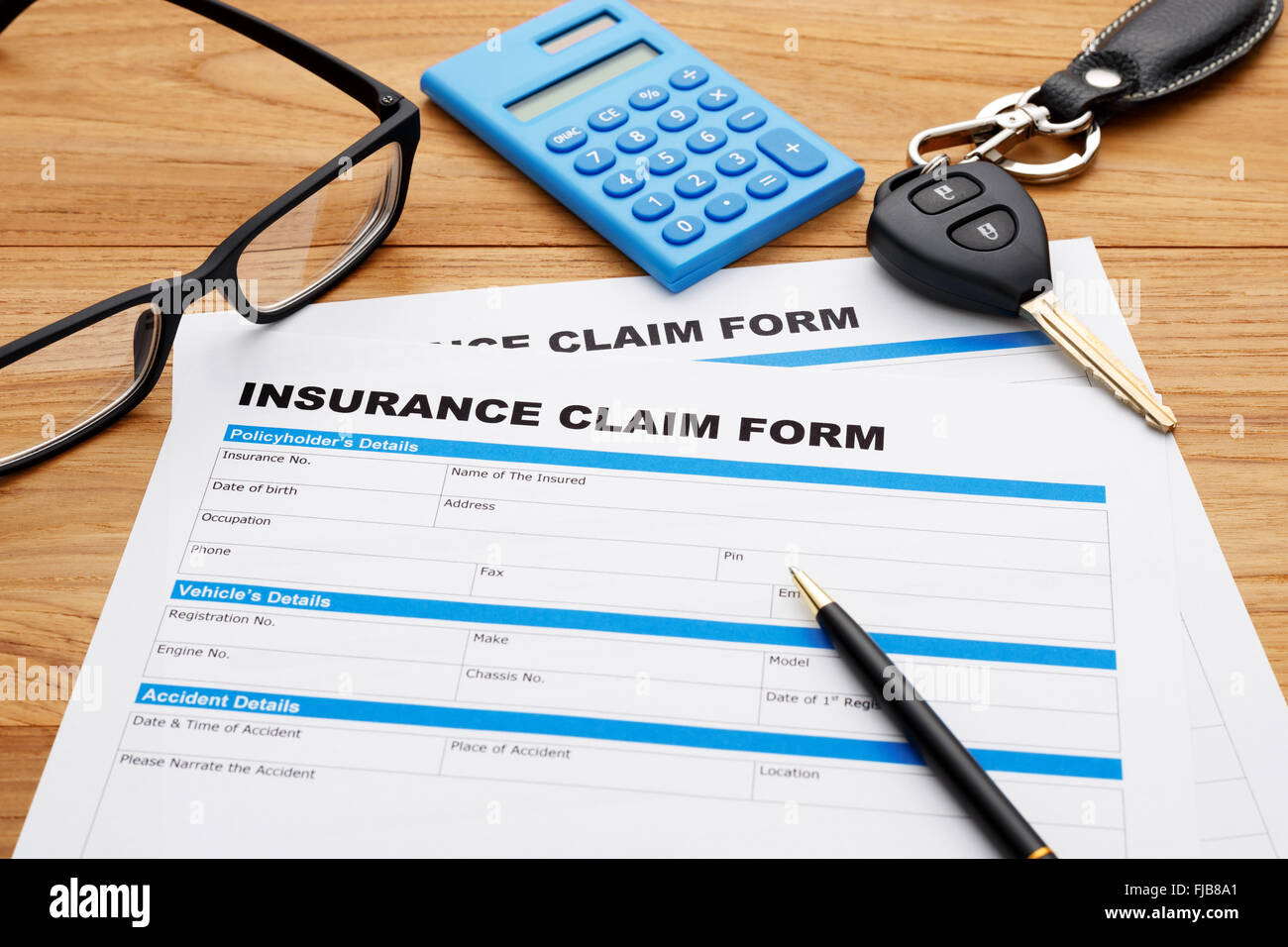 Insurance claim form with pen and car key on wood desk Stock Photo - Alamy