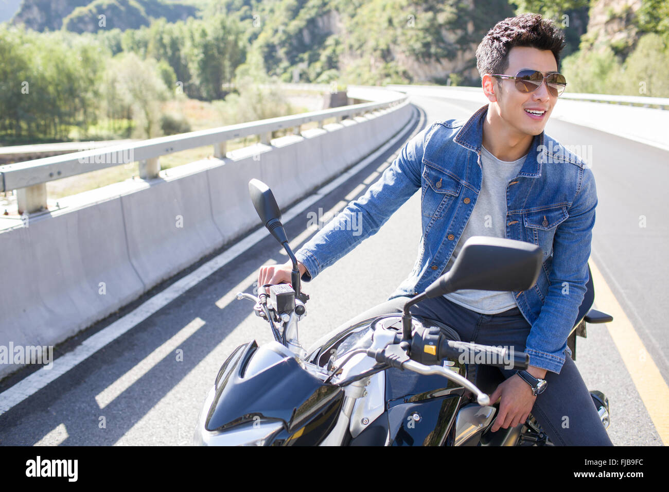 Young Chinese man riding motorcycle Stock Photo - Alamy