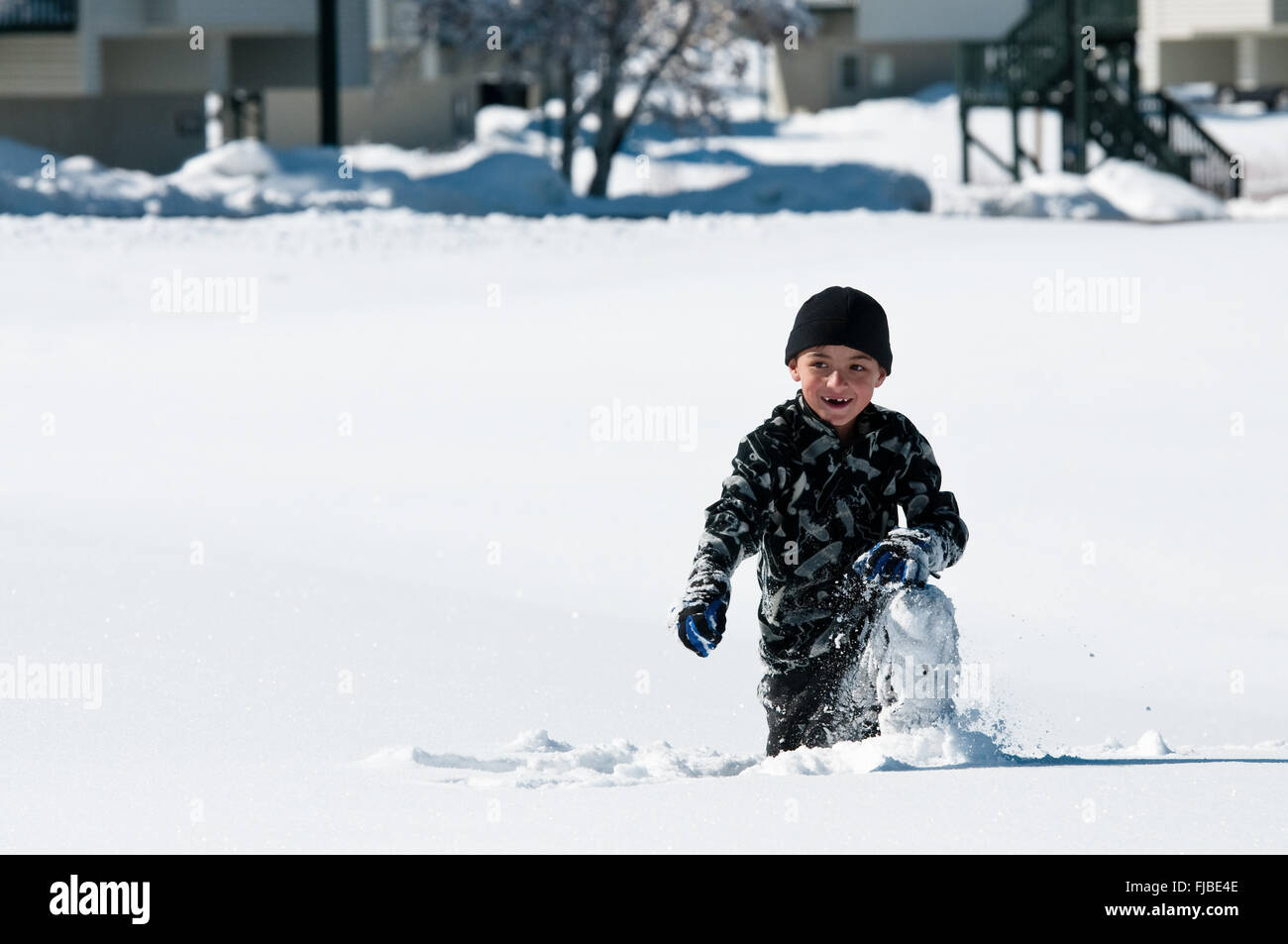Adorable little boy kneeling in the snow playing Stock Photo - Alamy