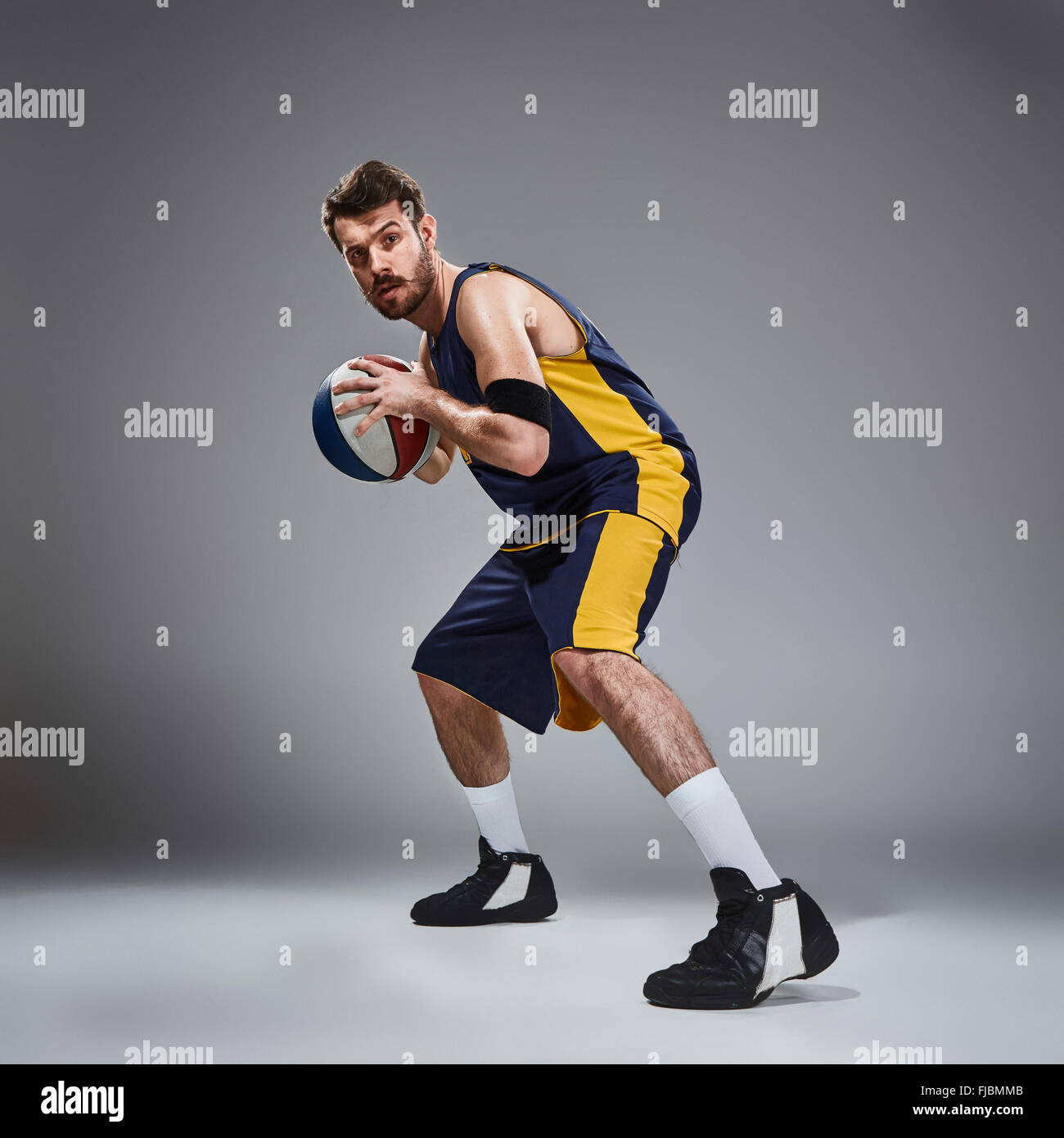 Full length portrait of a basketball player posing with a ball against ...