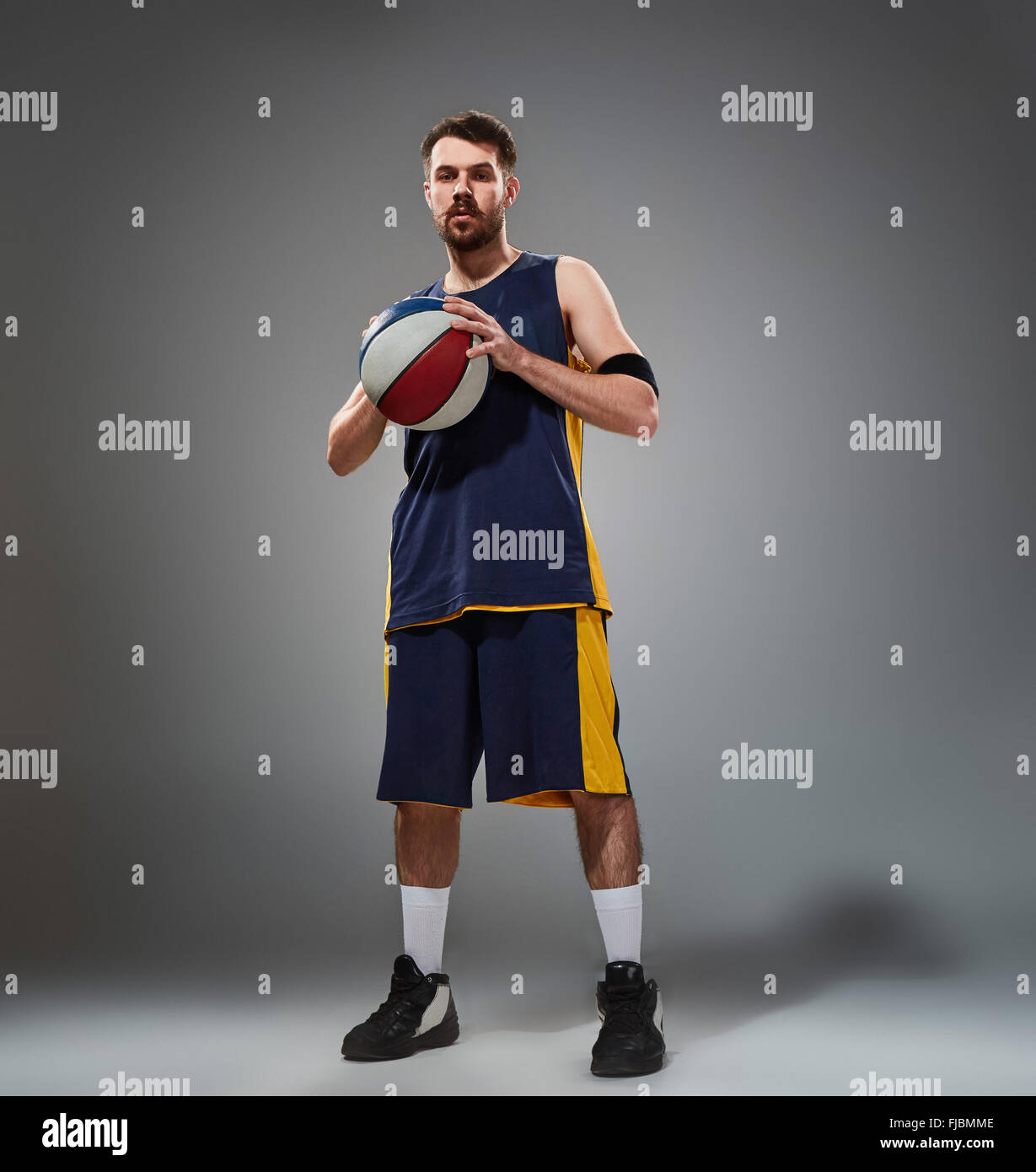 Full length portrait of a basketball player posing with a ball against ...