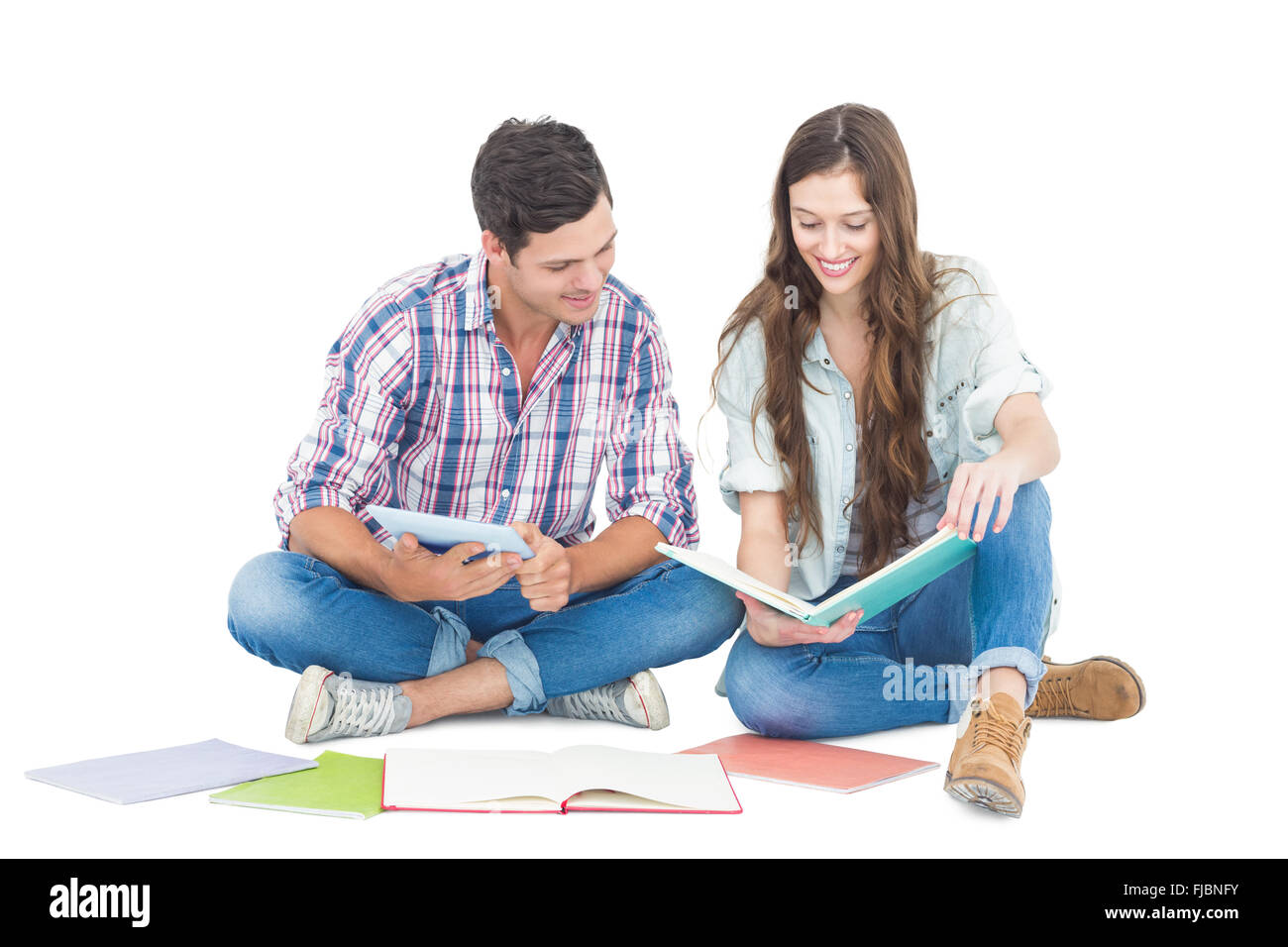 Happy couple studying with books and tablet while sitting on the floor ...