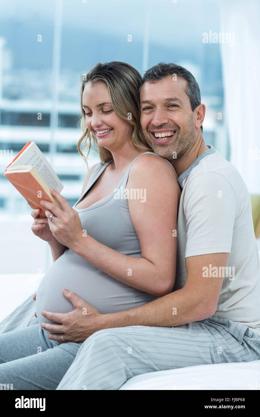 Expecting couple sitting on bed Stock Photo - Alamy