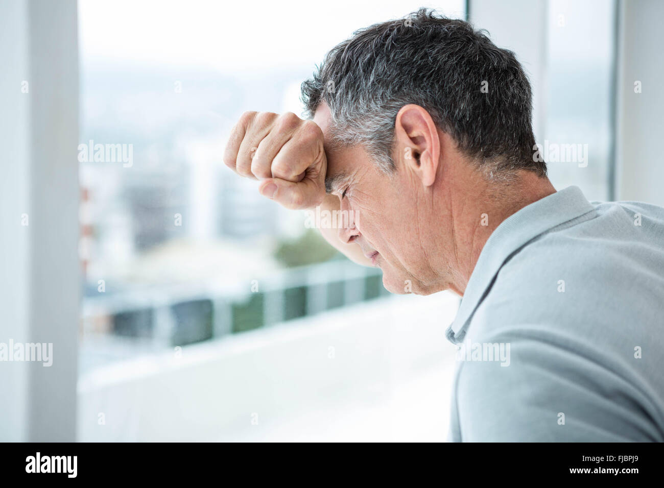Tensed man leaning on glass window Stock Photo - Alamy