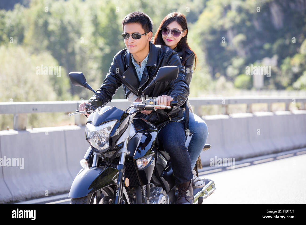 Young Chinese couple riding motorcycle together Stock Photo - Alamy
