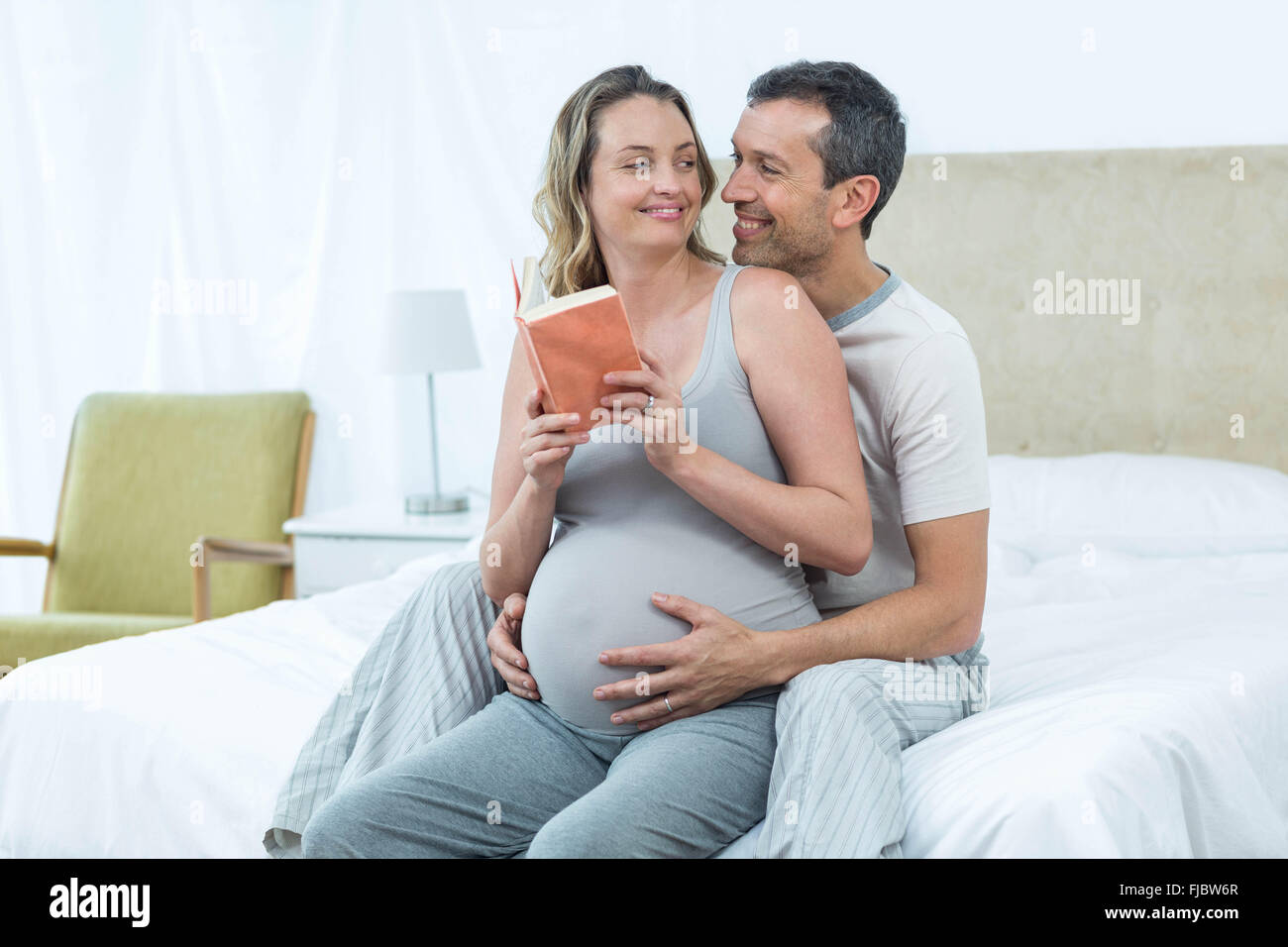 Expecting couple sitting on bed Stock Photo - Alamy