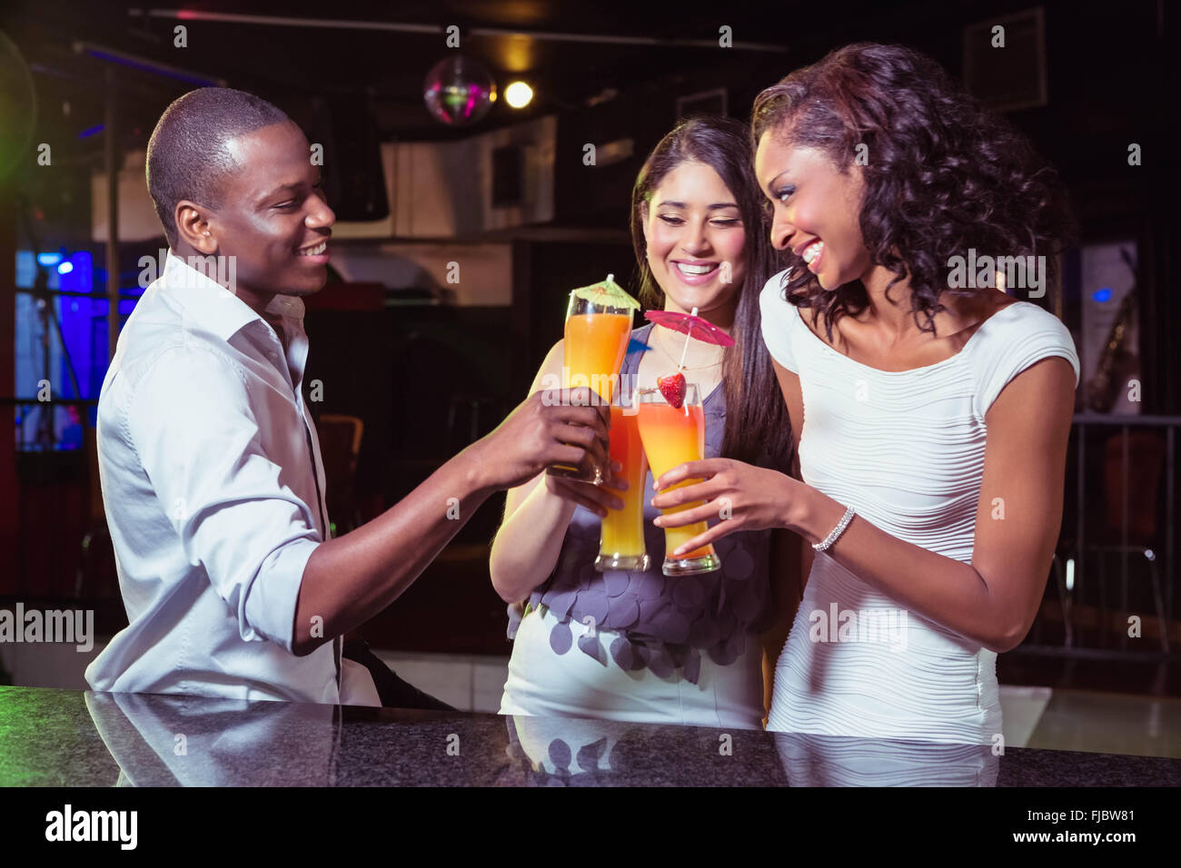 Young friends enjoying while having cocktail drinks at bar counter ...