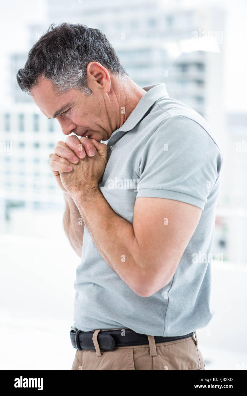 Tensed man standing against window Stock Photo - Alamy