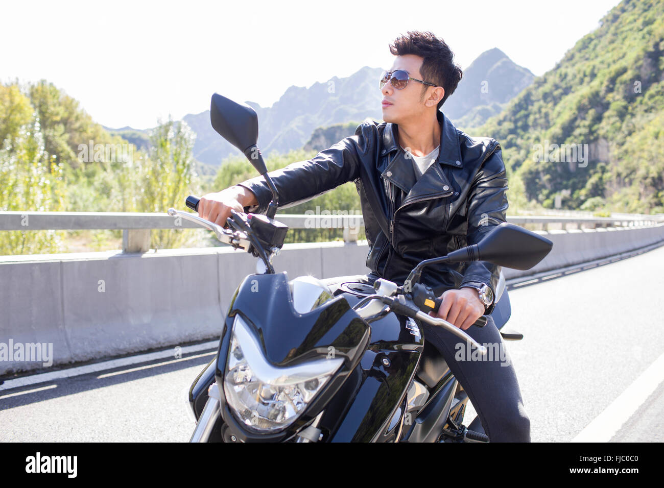 Young Chinese man riding motorcycle Stock Photo - Alamy