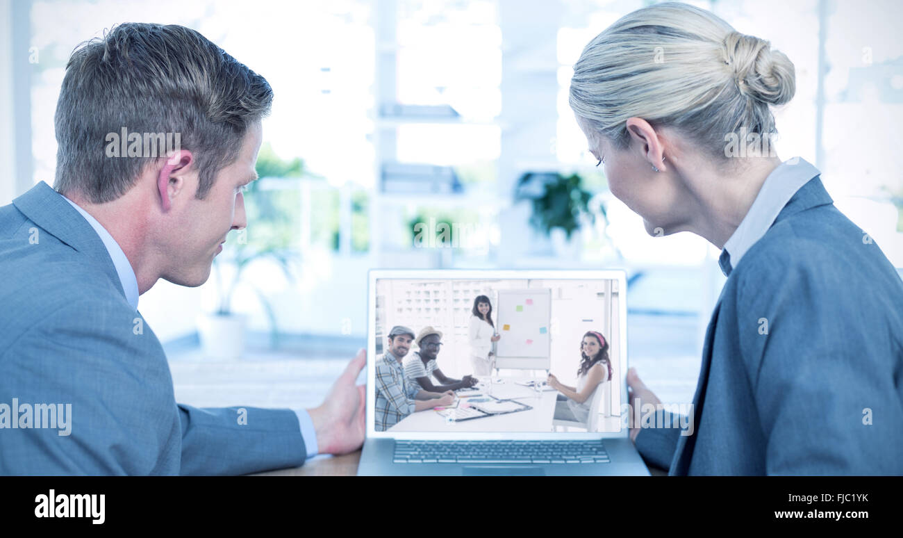 Composite image of business people looking at blank screen of laptop ...