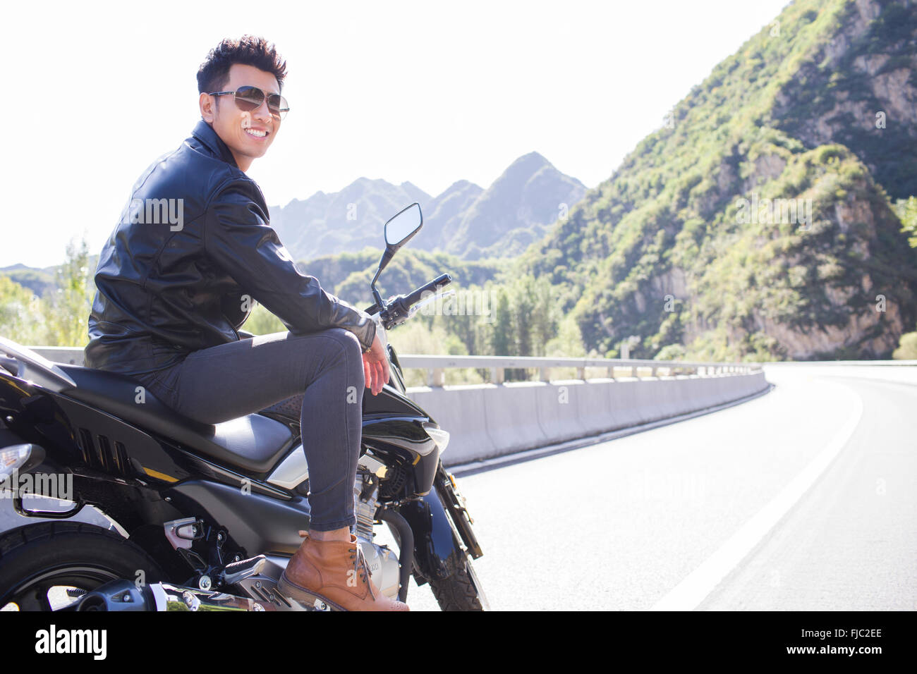 Young Chinese man riding motorcycle Stock Photo - Alamy