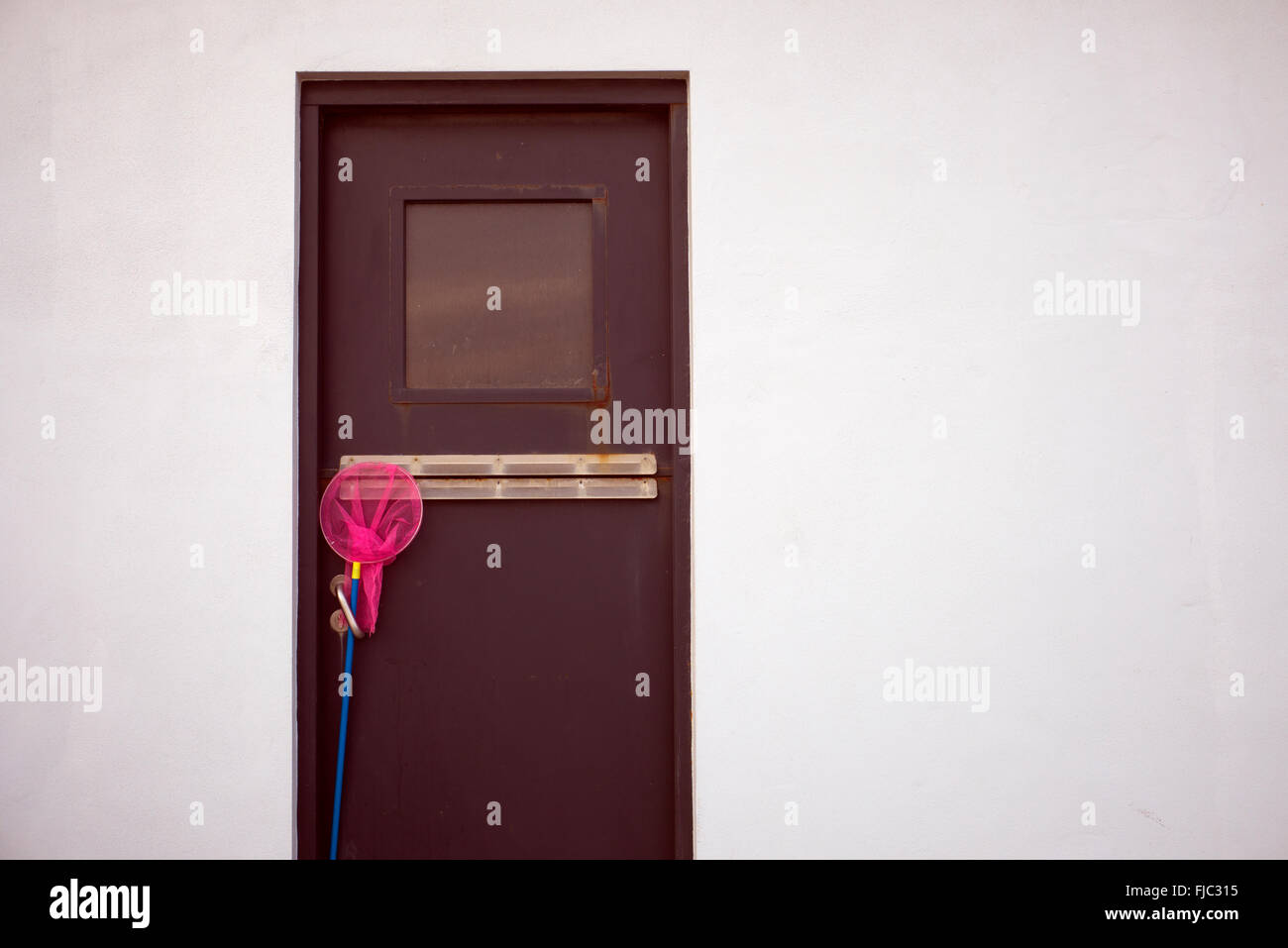 Child's fishing net propped against door in plain wall Stock Photo - Alamy