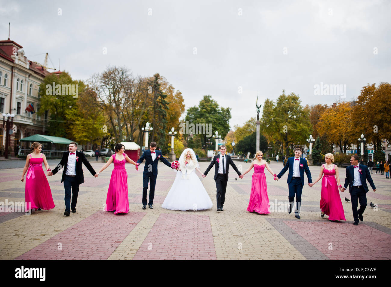 Group of wedding friends walking on line at square Stock Photo - Alamy