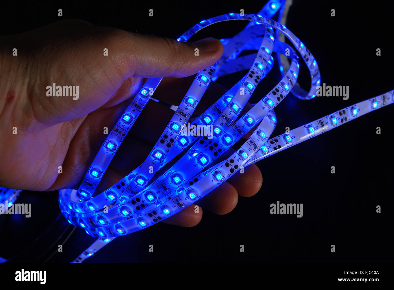 Blue led strip in the hand on the black background Stock Photo - Alamy