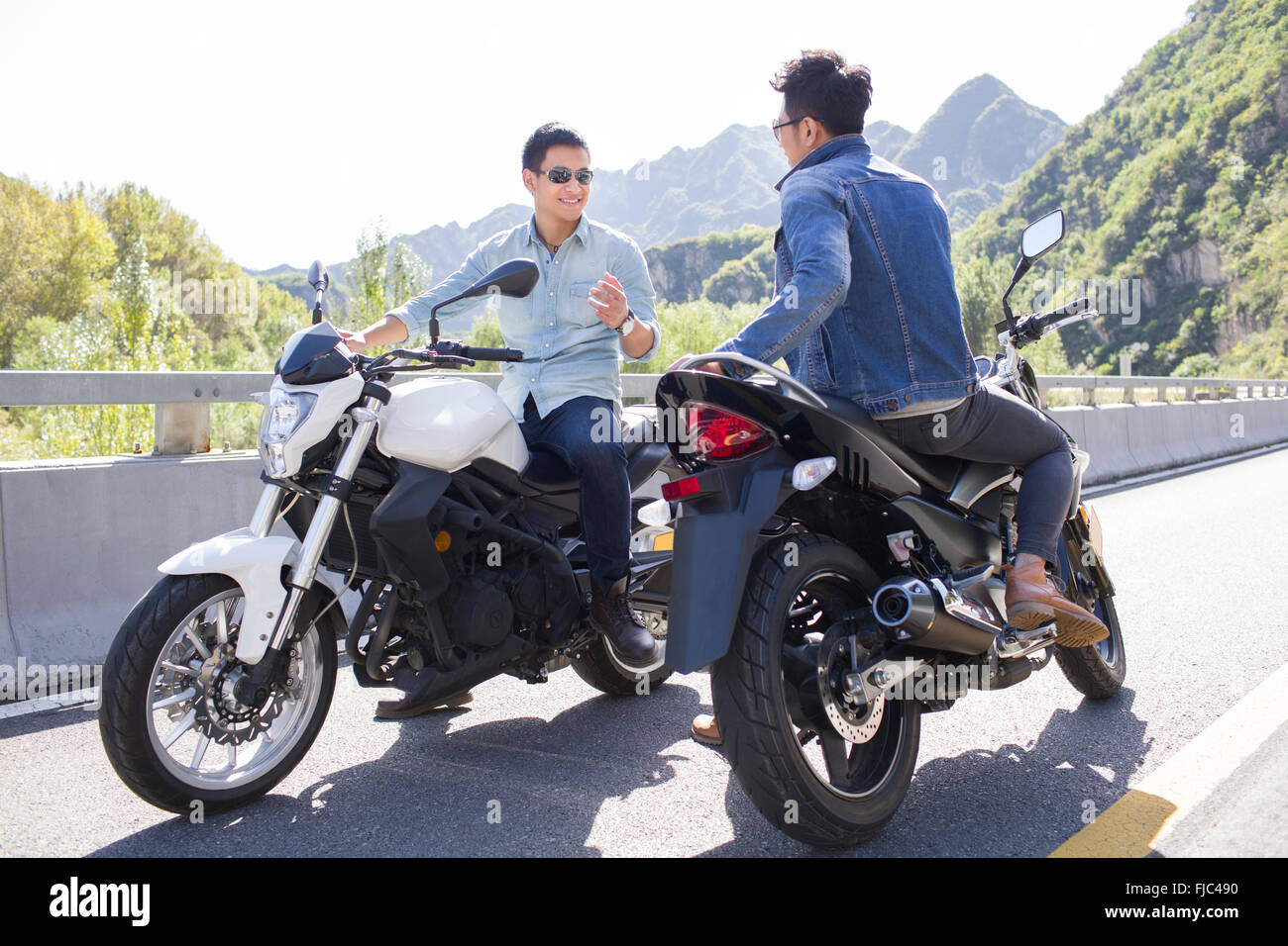 Young Chinese men riding motorcycle Stock Photo - Alamy