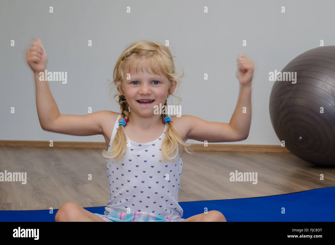 little blond girl with winner posture in gym matt Stock Photo - Alamy