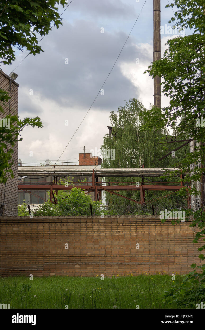 factory chimney rising above the fence with barbed wire Stock Photo - Alamy