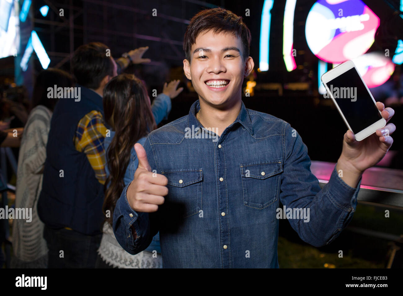 Young Chinese man showing smart phone at music festival Stock Photo - Alamy