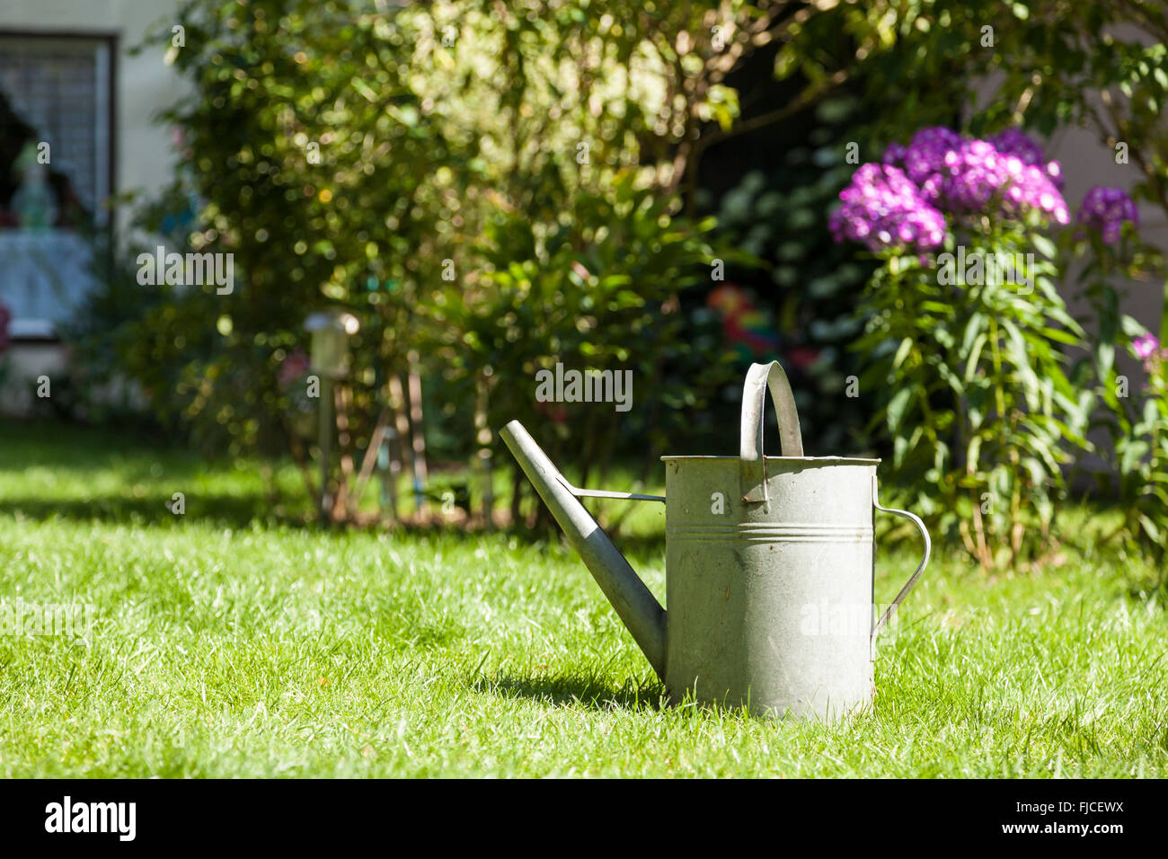 Watering can in garden Stock Photo - Alamy