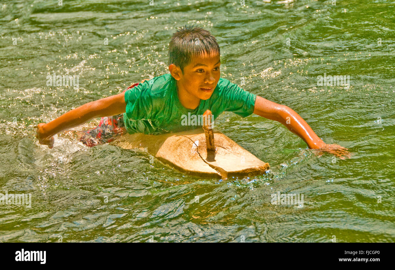 Indigenous Cabecar boy paddeling on surf board hand carved out of Balsa ...