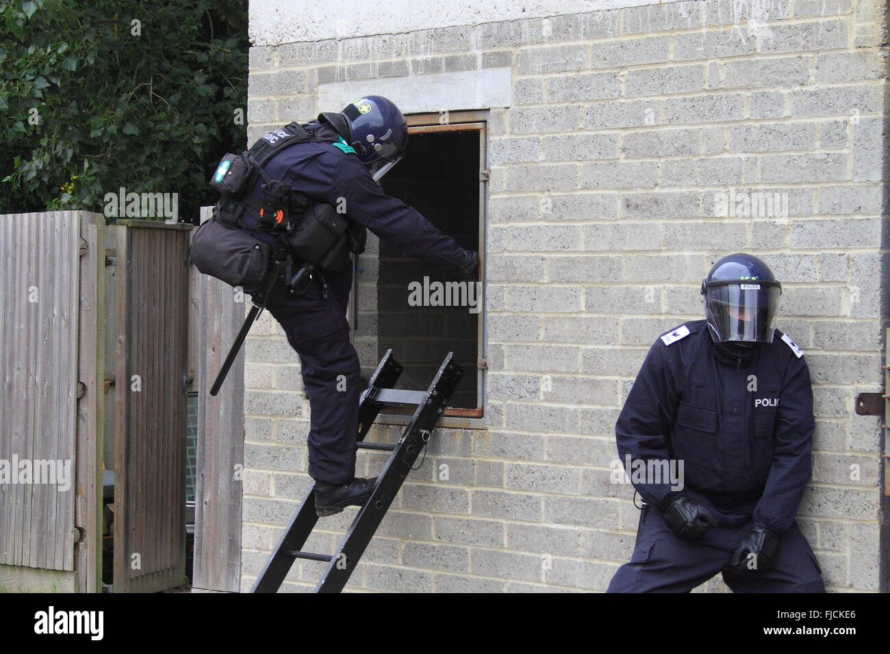 Police Rapid Entry Team use a ladder to climb through a smashed window ...
