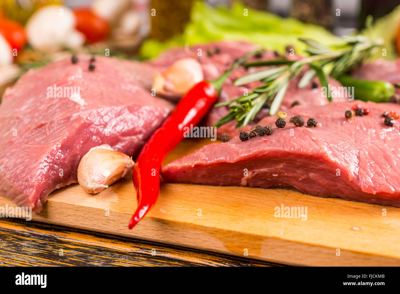 Close up view on fresh red hot chile pepper and slabs of raw meat ...