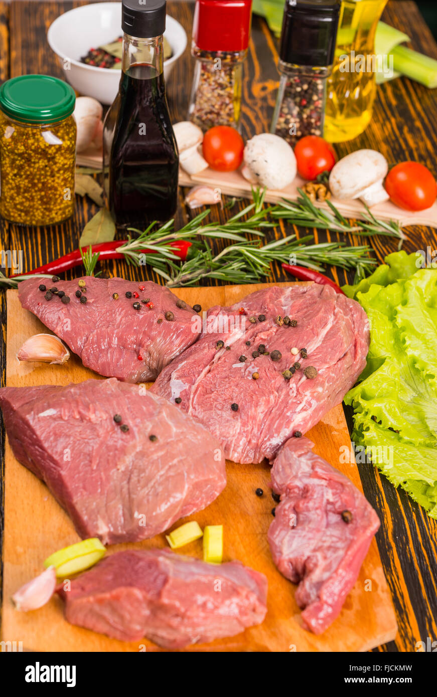 Five pieces of red meat covered with toppings of peppercorns on cutting ...