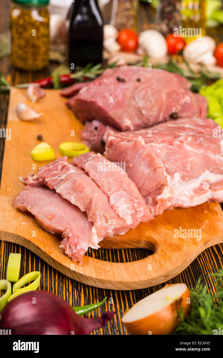 Chunks of raw red meat sliced on cutting board with onions in the ...