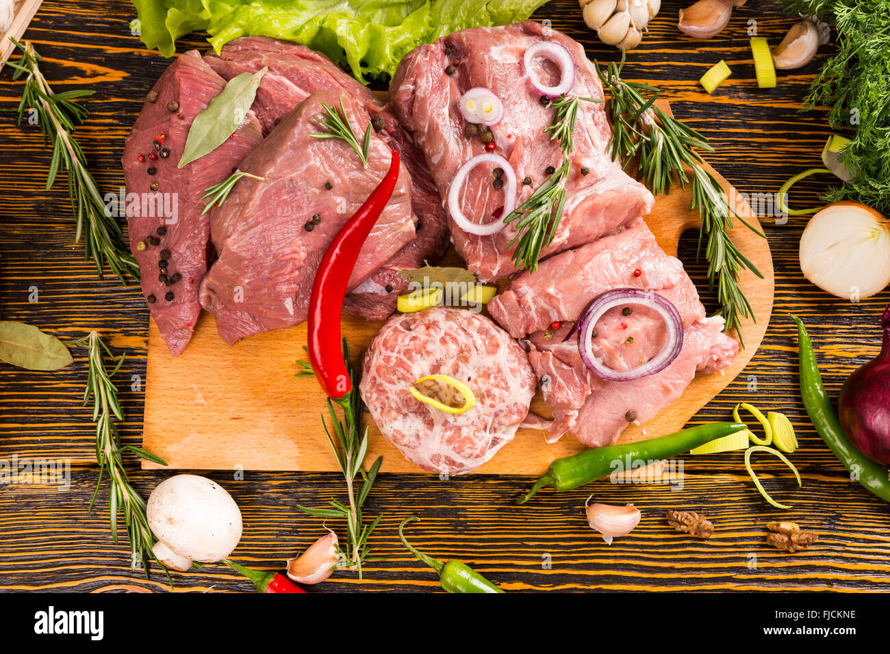 Various types of red raw meat with peppers, rosemary and spices on ...