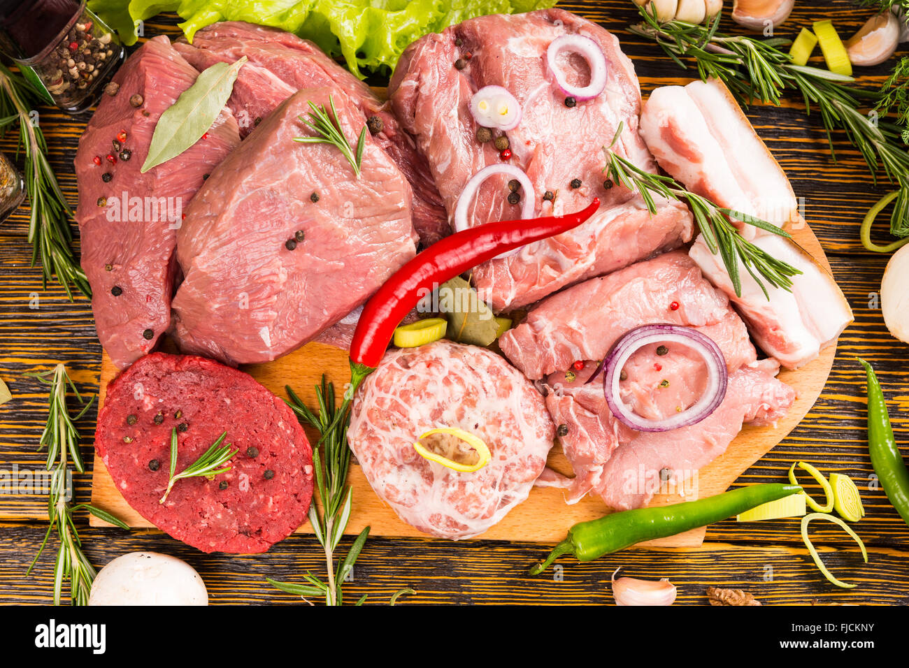 Cutting board overfilled with large pieces of meat covered with herbs ...