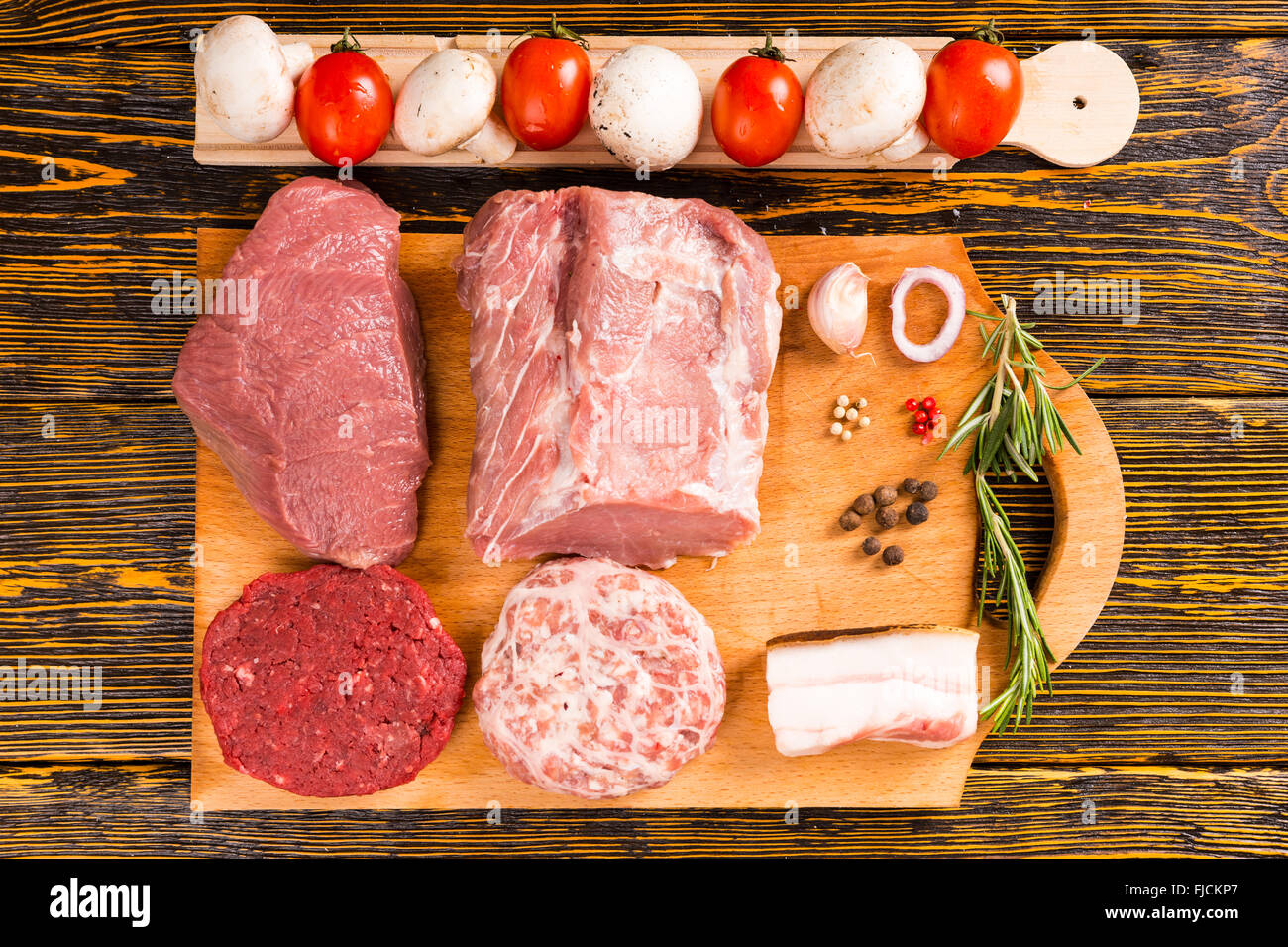 Top down view of matching pieces of raw red meat and pork on cutting ...