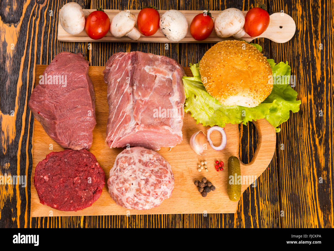 Raw red lunch meat, peppers, garlic, tomato, bun and other vegetables ...