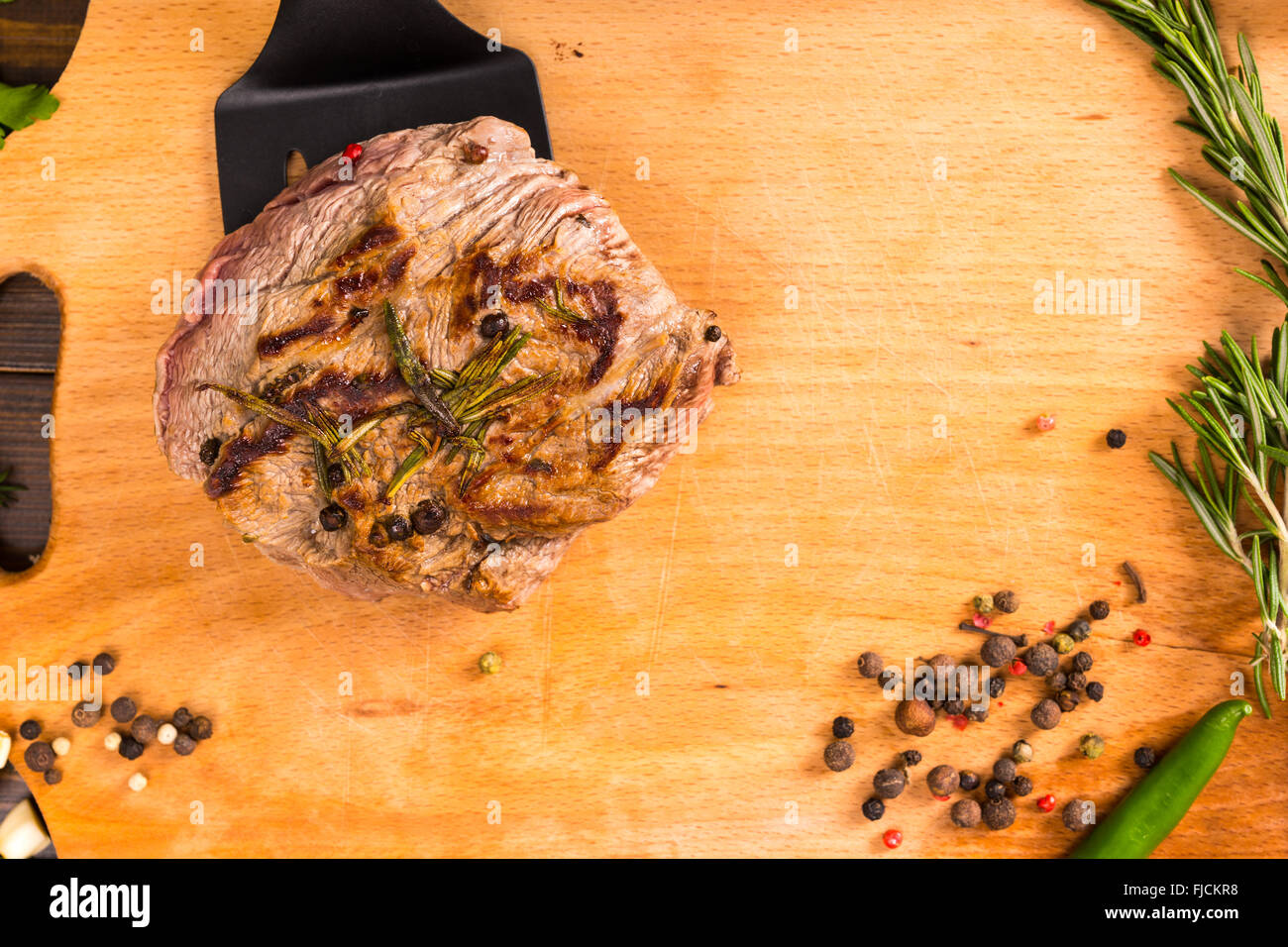 Single cooked beef patty in spatula with herbs and various peppers over ...
