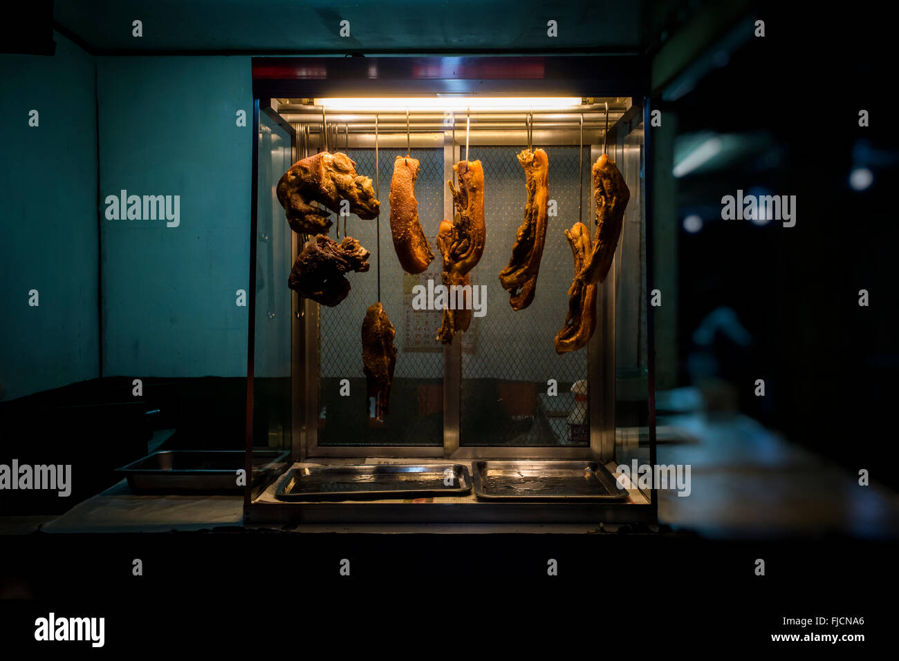 Cooked pork meat hanging in glass cage Stock Photo - Alamy